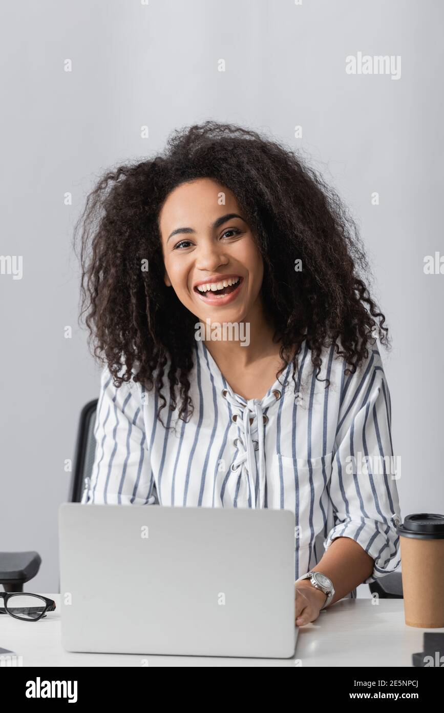 happy african american freelancer smiling while looking at camera near ...