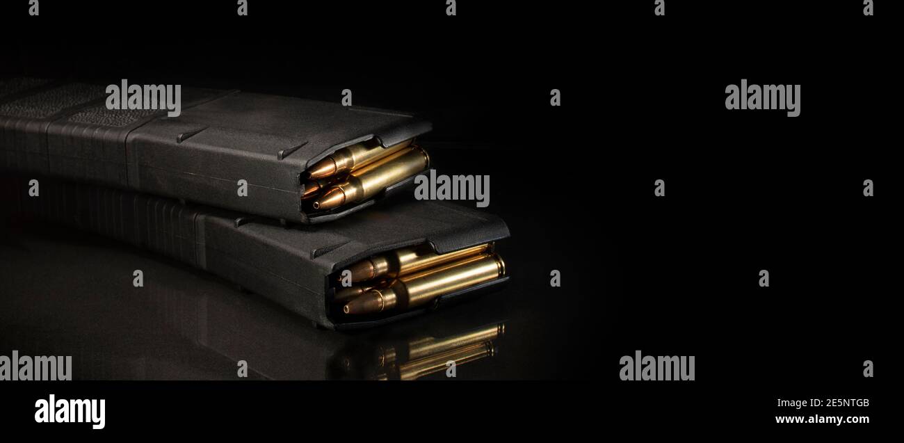 A pair of AR-15 magazines loaded with ammunition on a black background ...