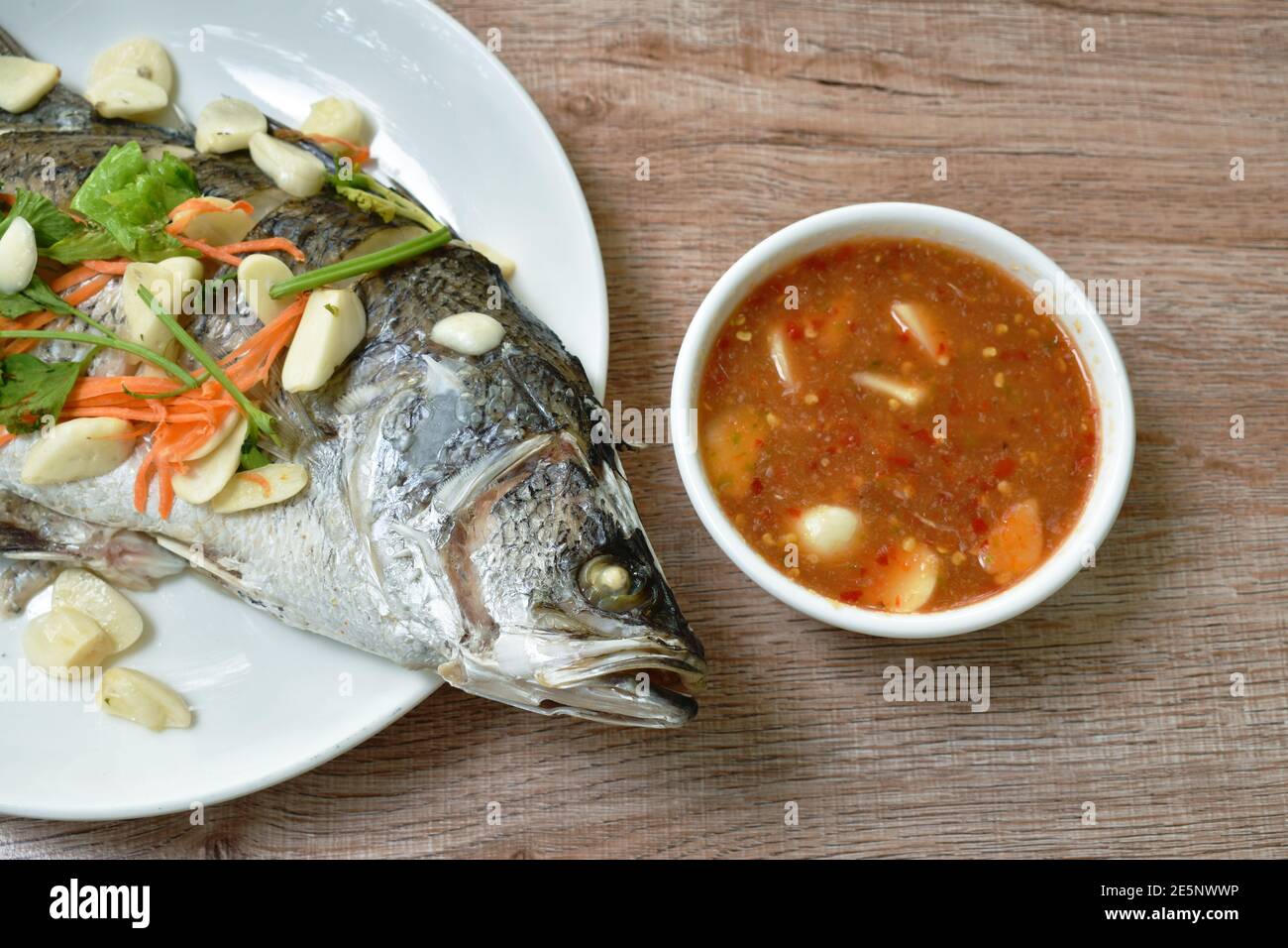 steamed bass fish with garlic dipping spicy sauce on table Stock Photo ...