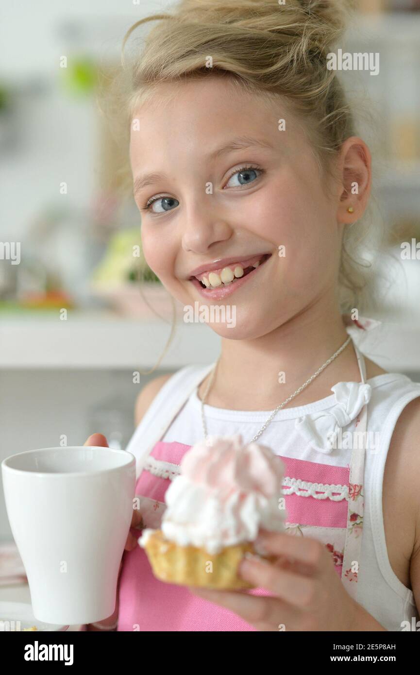 Cute girl eating cake in the kitchen Stock Photo - Alamy