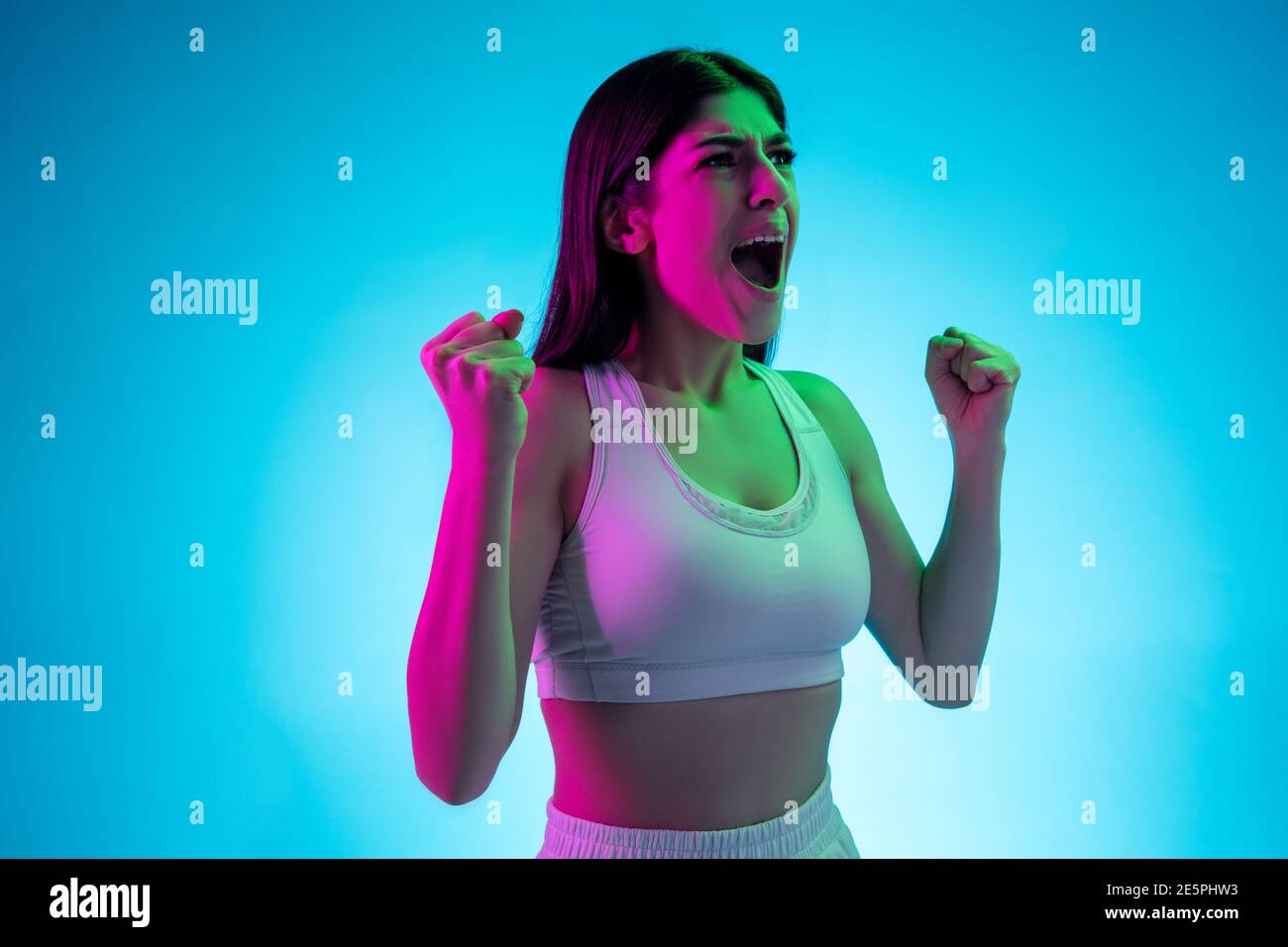 Excited screaming. Brunette woman's portrait isolated on blue studio ...