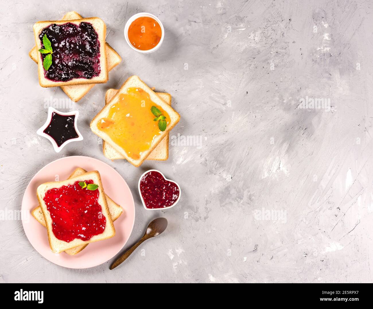 Delicious toasts with various sweet jams on grey background. Copyspace ...
