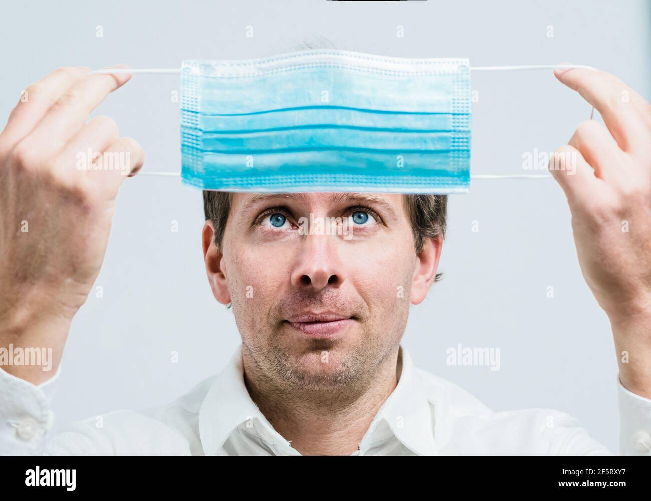 Closeup of young man looking at mask holding it on hands. White ...