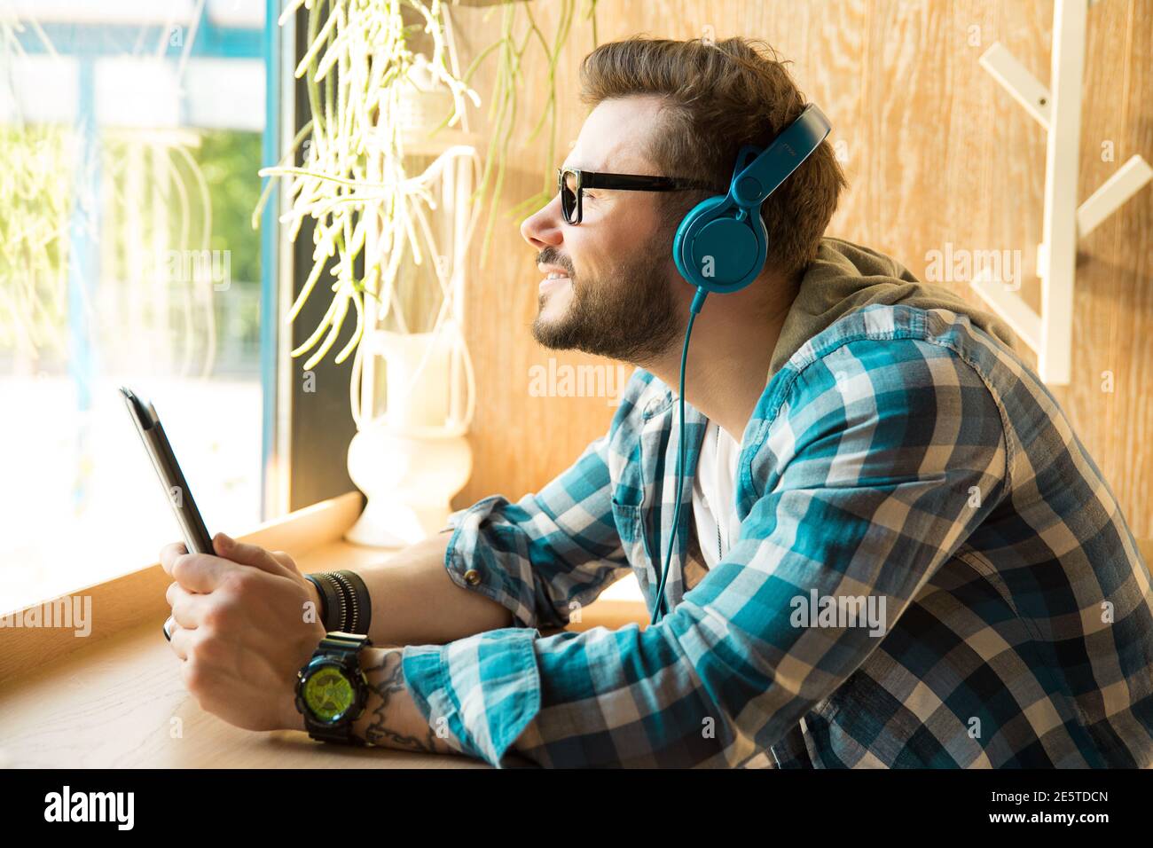 Happy young freelancer man listening to music using tablet computer ...
