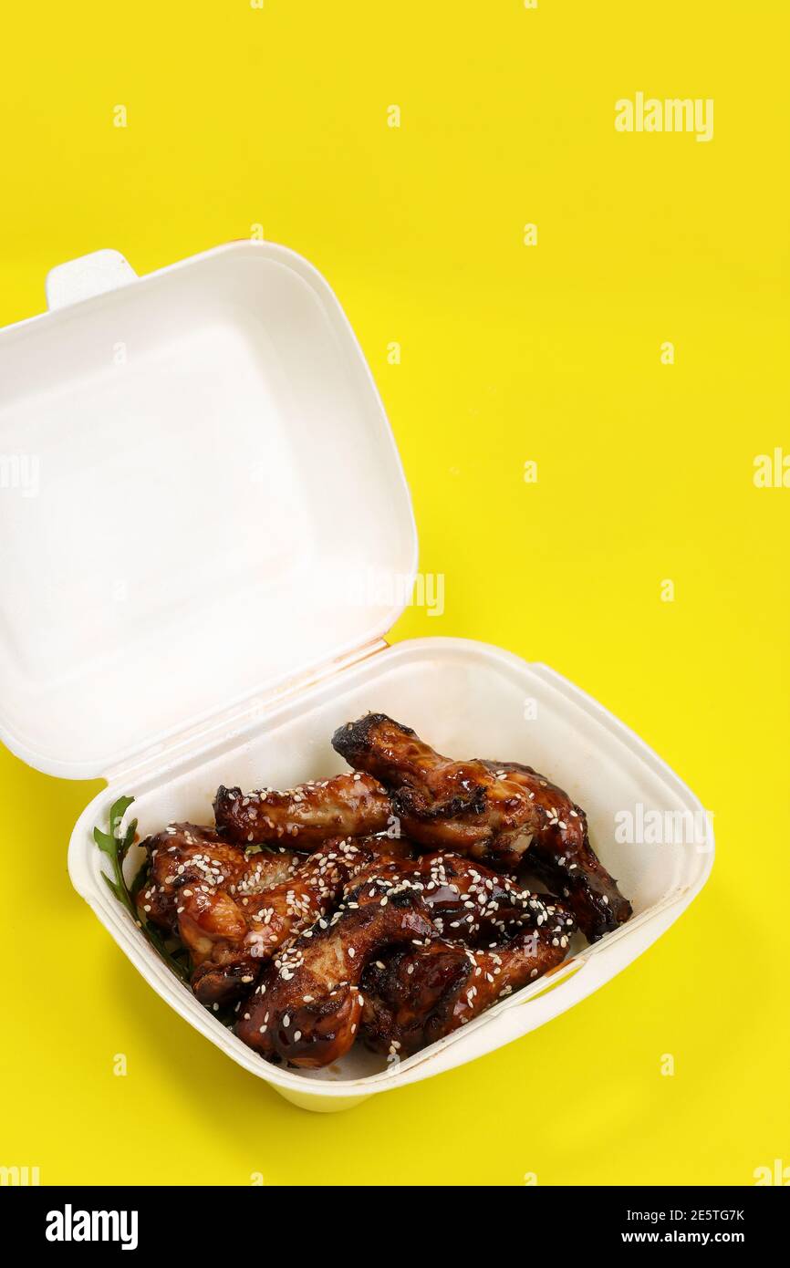 Fresh cooked delicious chicken wings in a plastic container isolated on ...