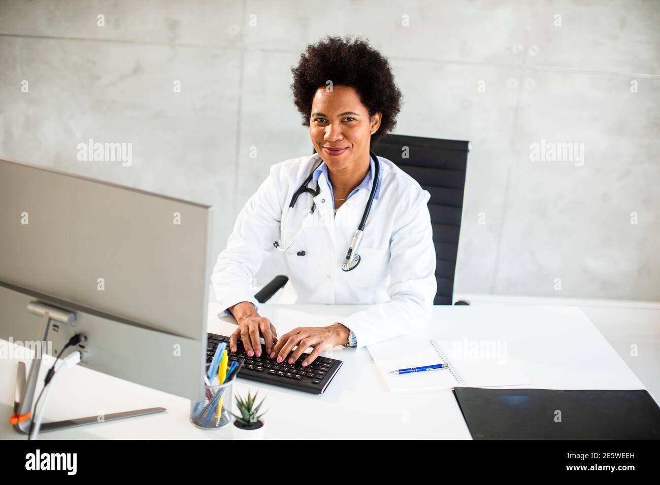 Female doctor sitting behind desk hi-res stock photography and images ...