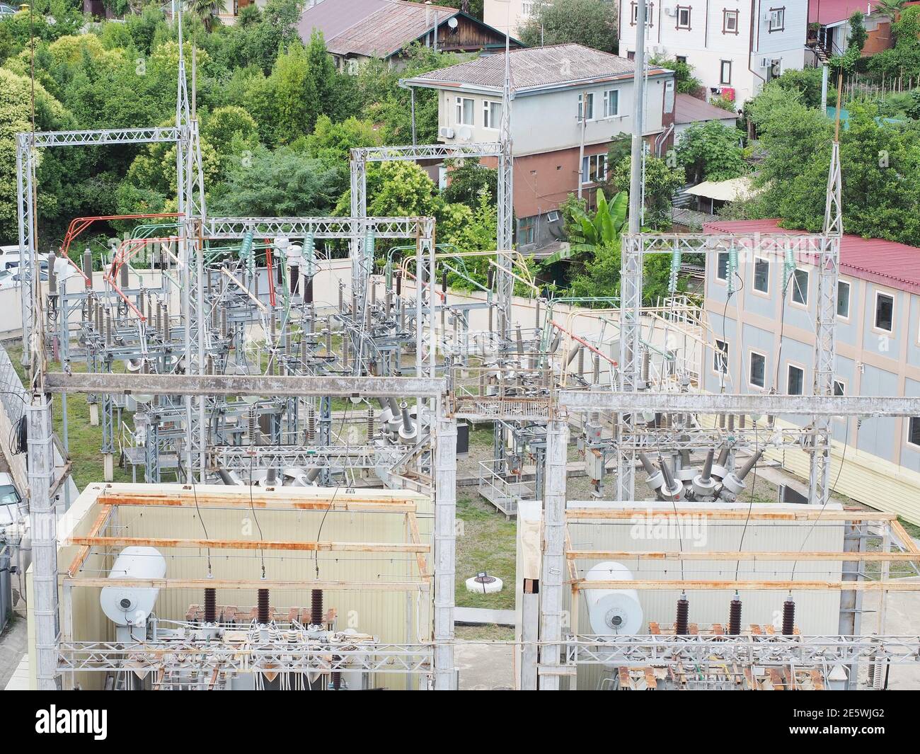A power plant with many metal structures surrounded by fence with trees ...