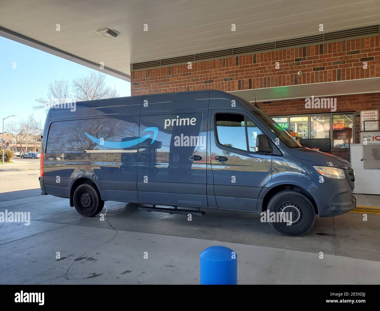 Profile view of a blue Amazon Prime van parked under an overhang at a ...