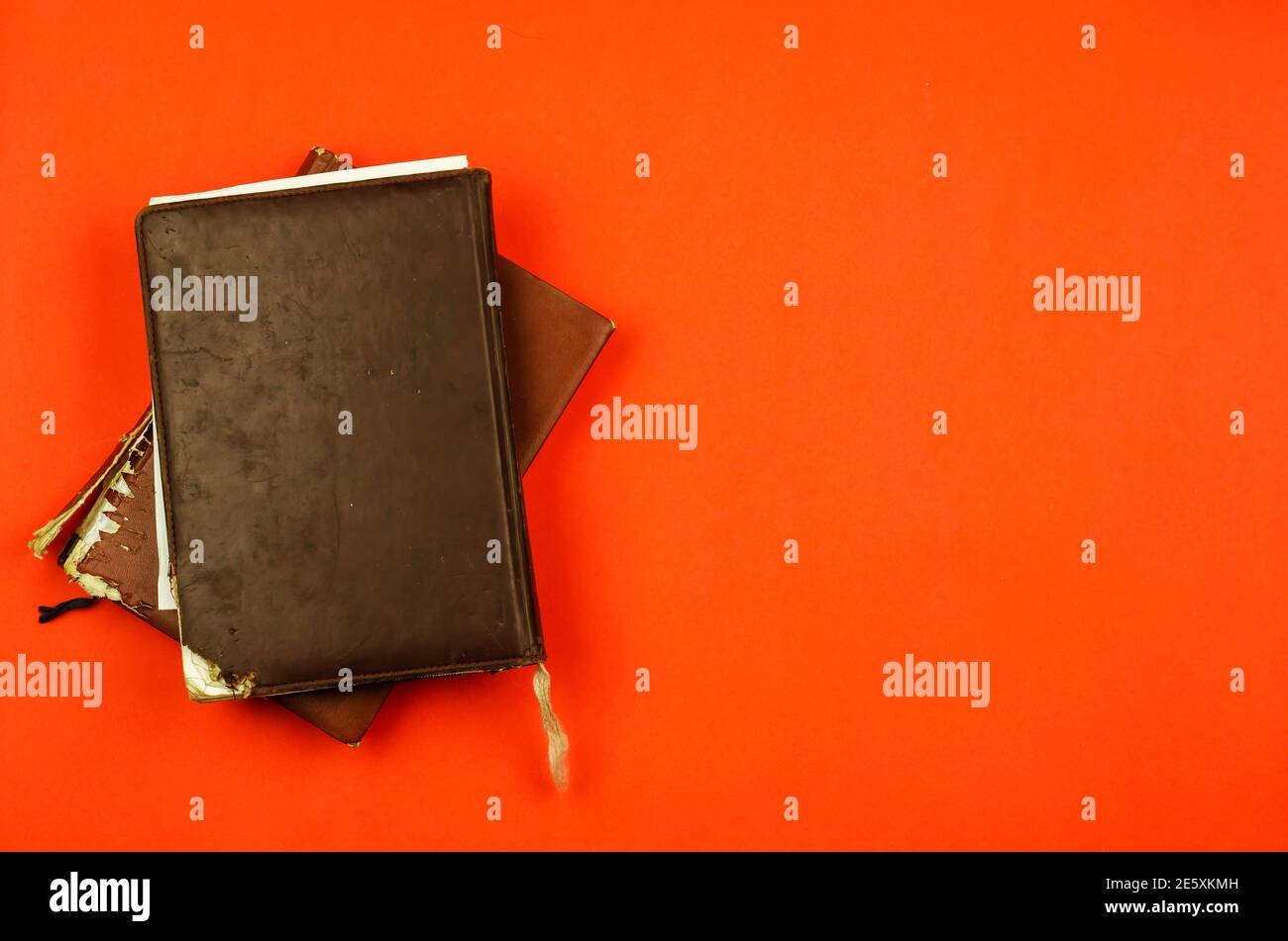 Old Tattered diaries on red background. Two closed Diaries in brown and ...