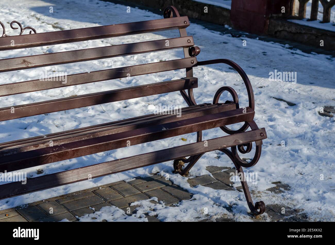 Empty Beautiful brown bench on a winter city street. Wood and wrought ...