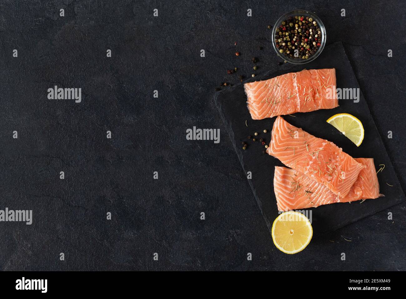 Fresh raw salmon fish fillet with paper spice and slices of lemon on ...