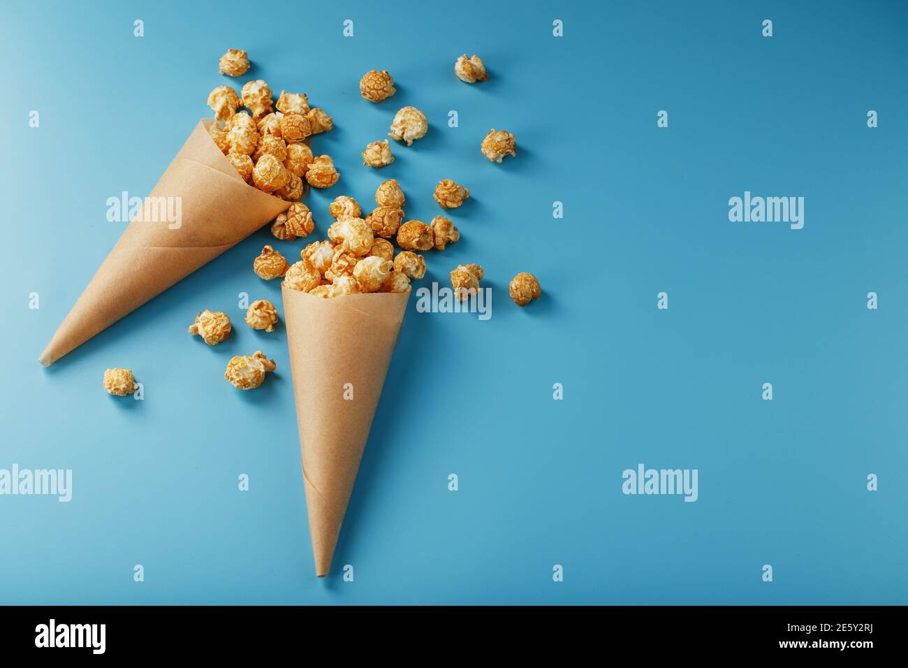 Caramel popcorn in a paper envelope on a blue background. Delicious ...