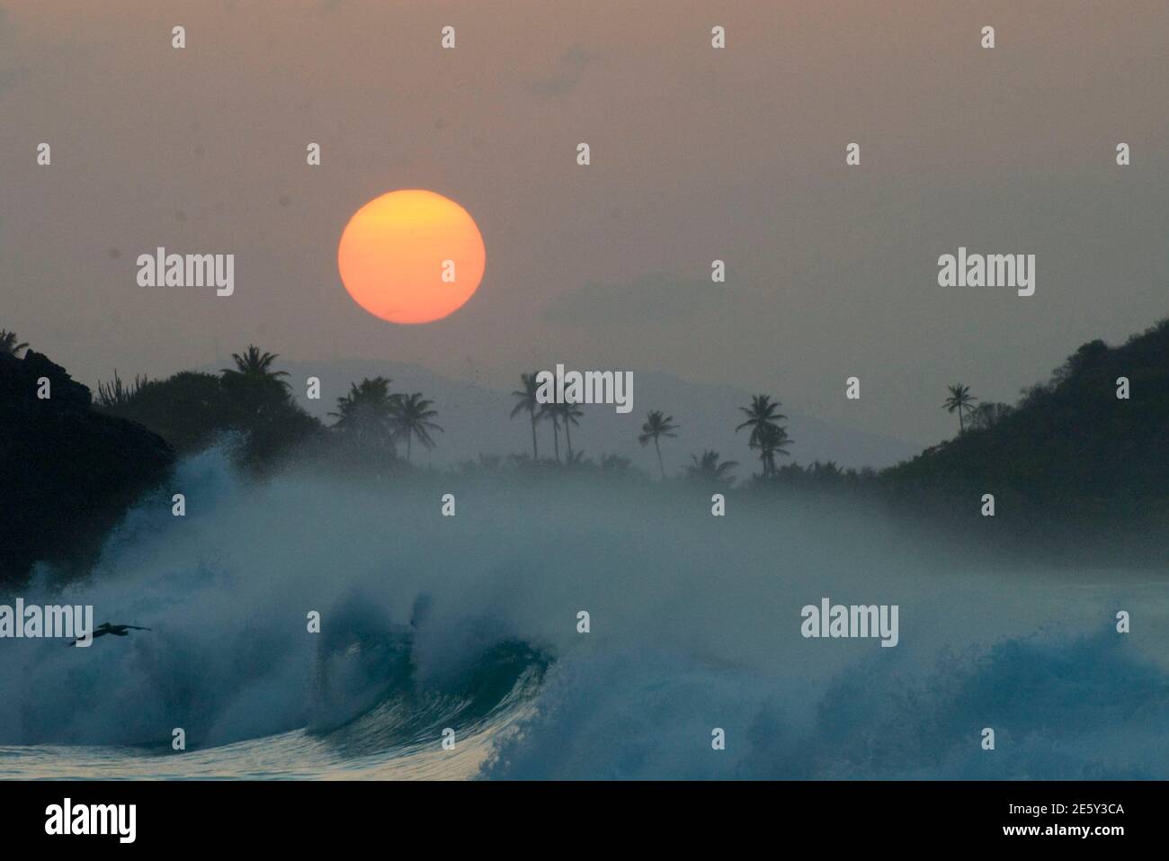 Orange Sun setting over tropical beach scene with waves crashing Stock ...
