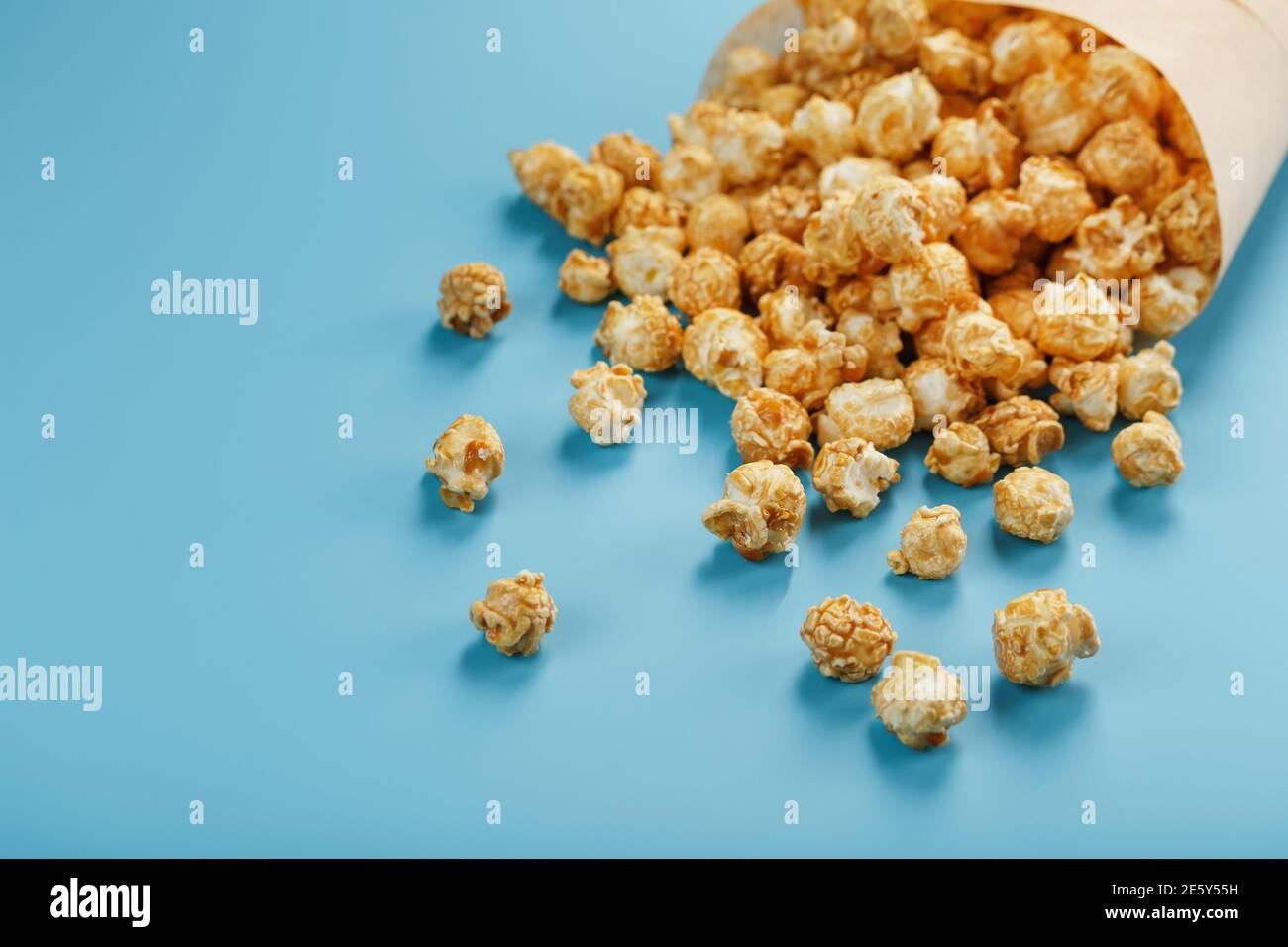 Popcorn in caramel glaze in a paper envelope on a blue background ...