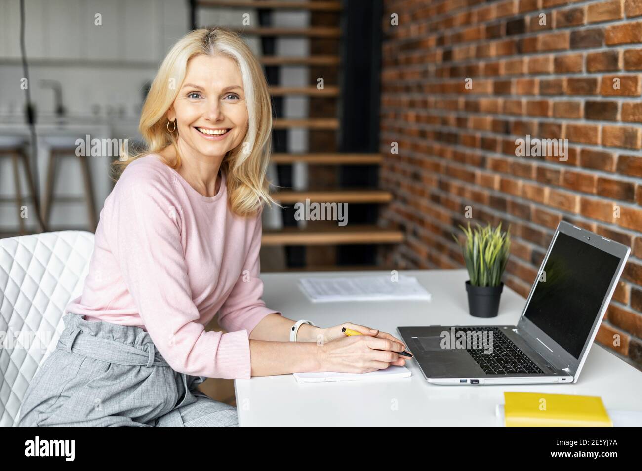 Enchanting middle-aged businesswoman looks at camera and smiles. Close ...
