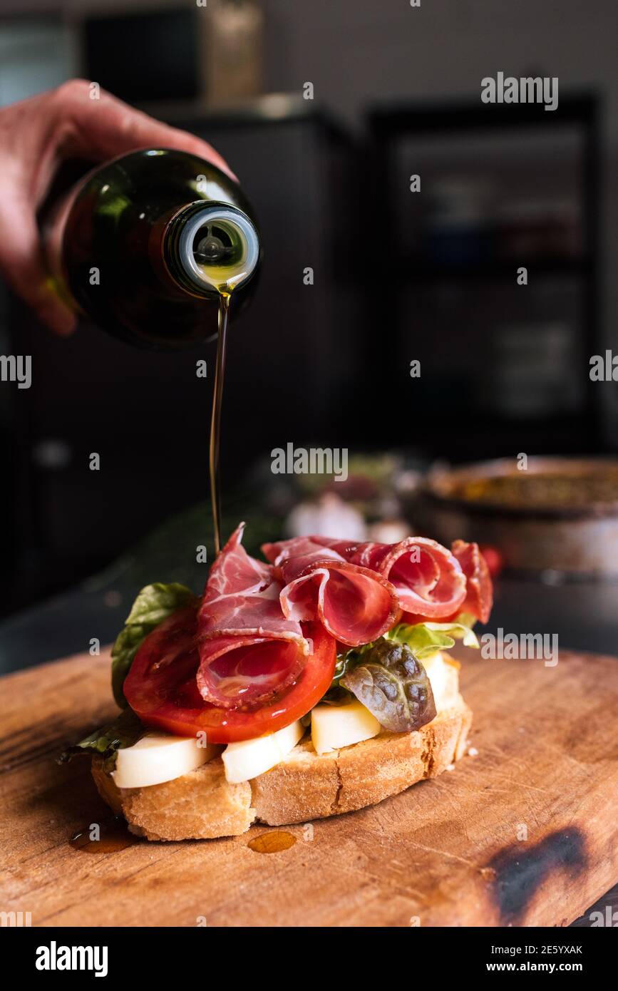 Stock photo of faceless chef pouring olive oil in yummy toast of ham ...