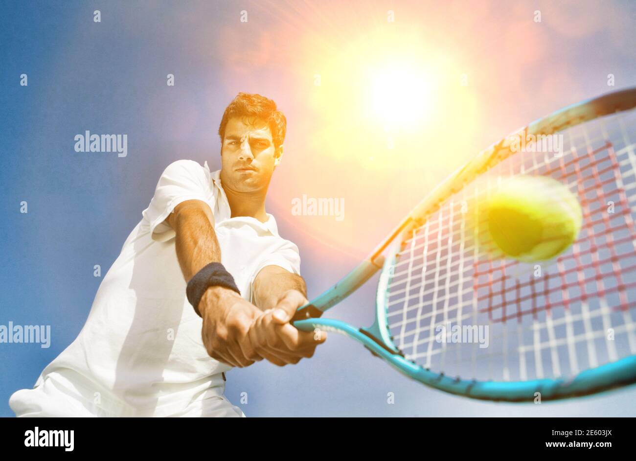 Low angle view of determined young man playing tennis with yellow lens ...