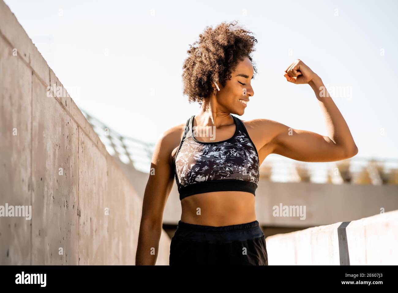 Afro athlete woman flexing and showing muscles Stock Photo - Alamy