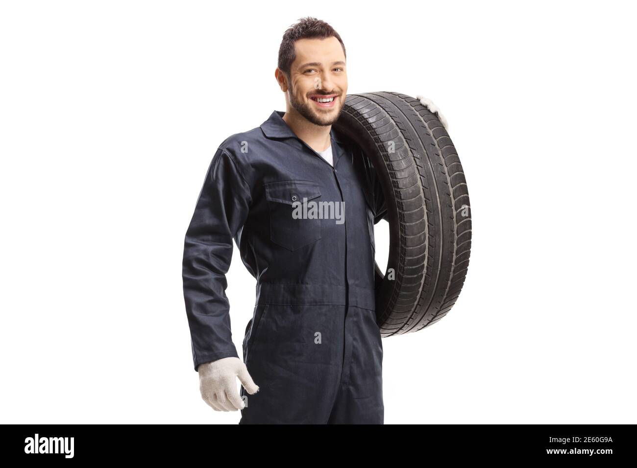 Mechanic holding a car tire and smiling at the camera isolated on white ...