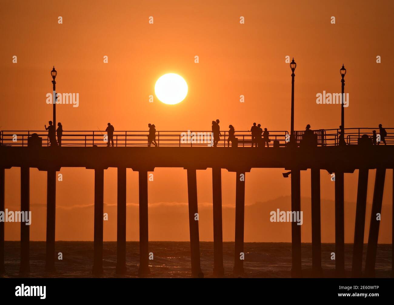 Sunset landscape with people silhouettes on Huntington Beach Pier in ...