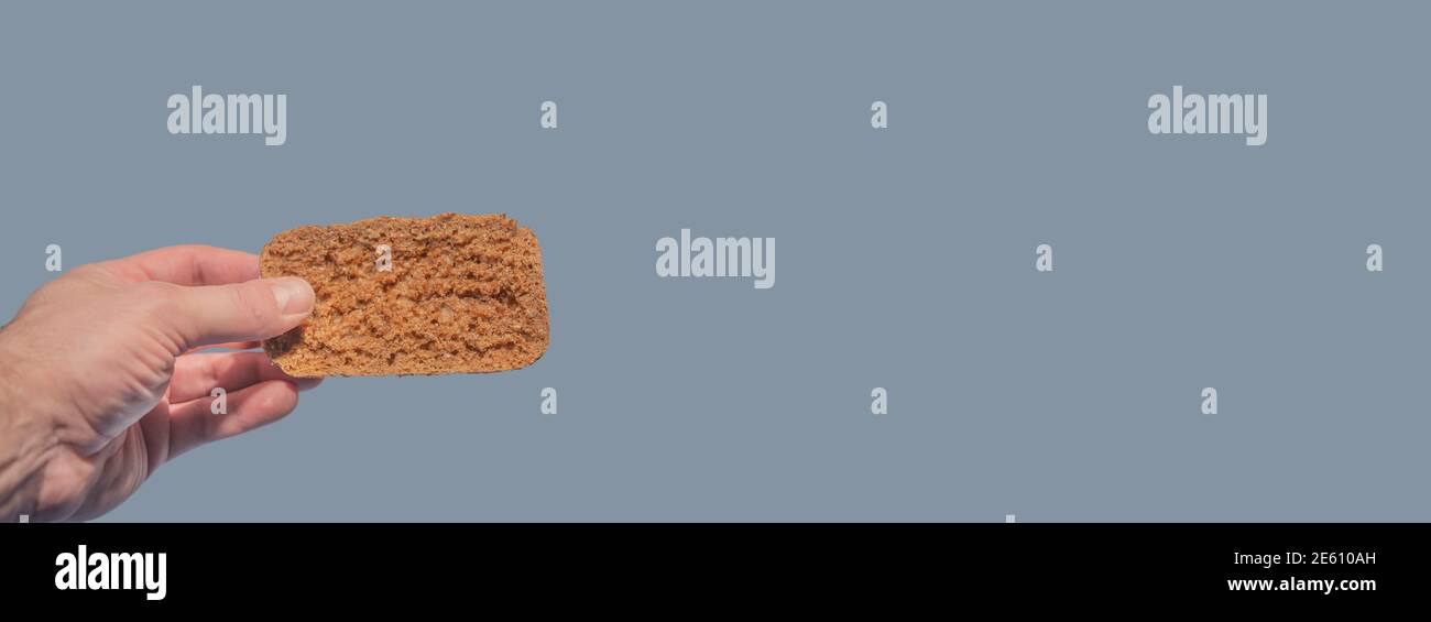 Banner with single piece of bread hold by a man hand at solid light ...