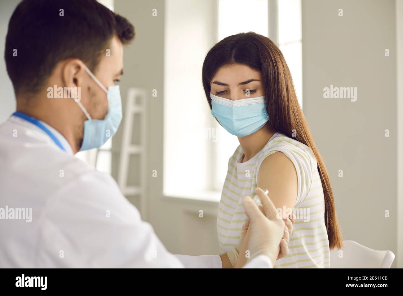 Doctor giving vaccine shot to young woman during immunization campaign ...