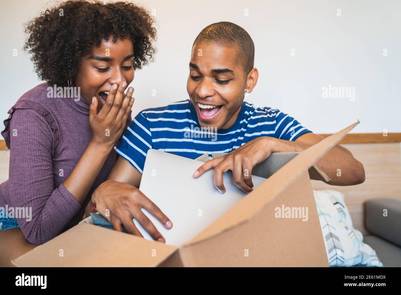 Young couple opening a package with a laptop inside Stock Photo - Alamy