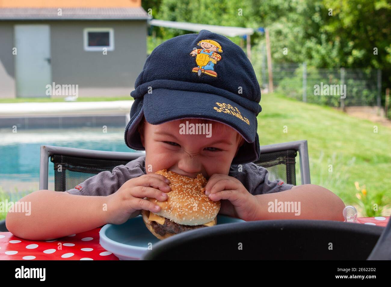 Little boy eating a burger in the garden Stock Photo - Alamy