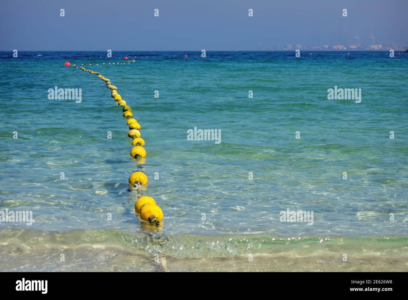 Seascape with floating buoys and rope dividing area on beach. Clear ...