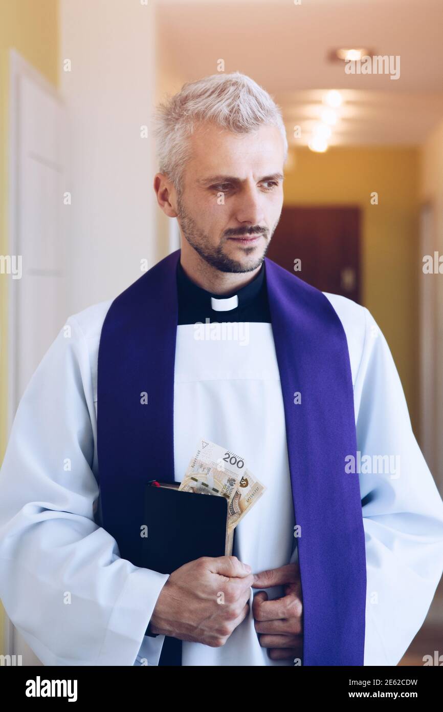 Polish catholic priest holding and counting money during pastoral visit ...