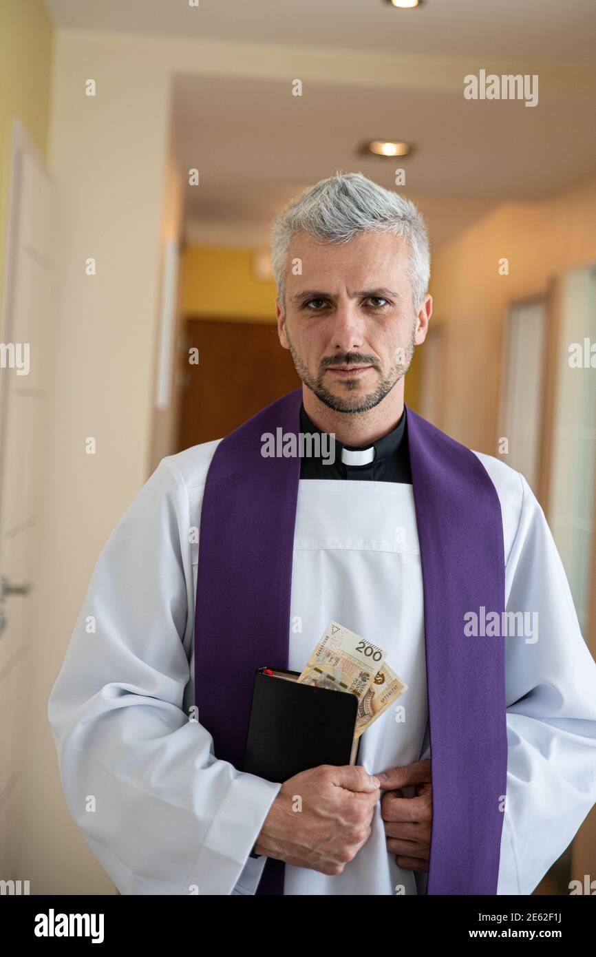 During a pastoral visit, a handsome young priest holds an envelope with ...