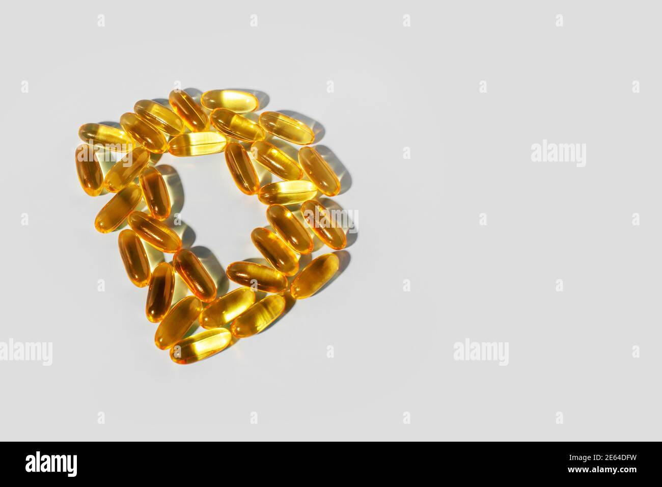 Yellow gelatin capsules on a gray background in the shape of the letter ...