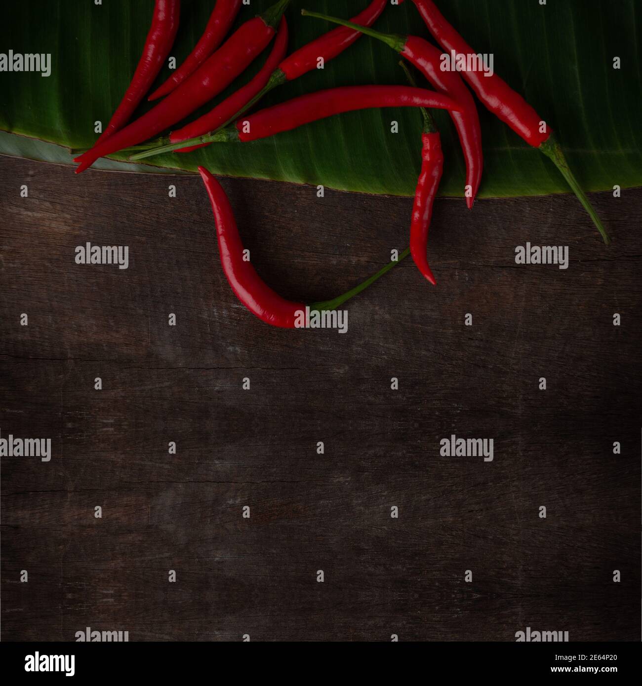 Red chilli on banana leaf ready for cooking shot on rustic wooden table ...