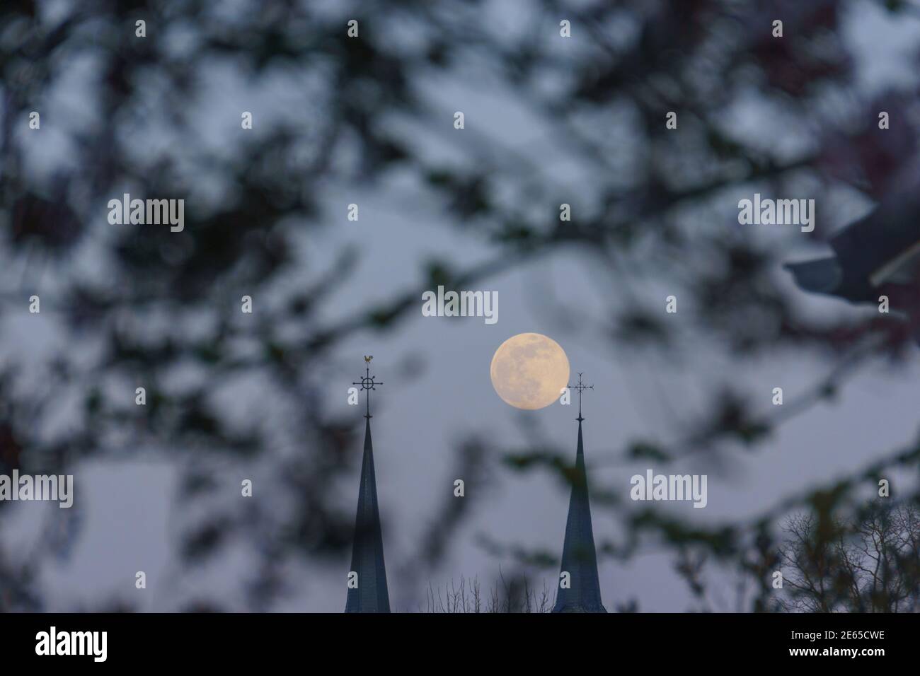 Full moon in between two church towers in the blue evening sky with ...