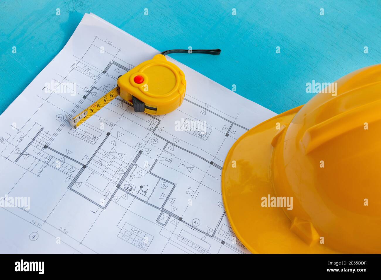 Construction drawings, safety helmets and tape measure on the blue ...