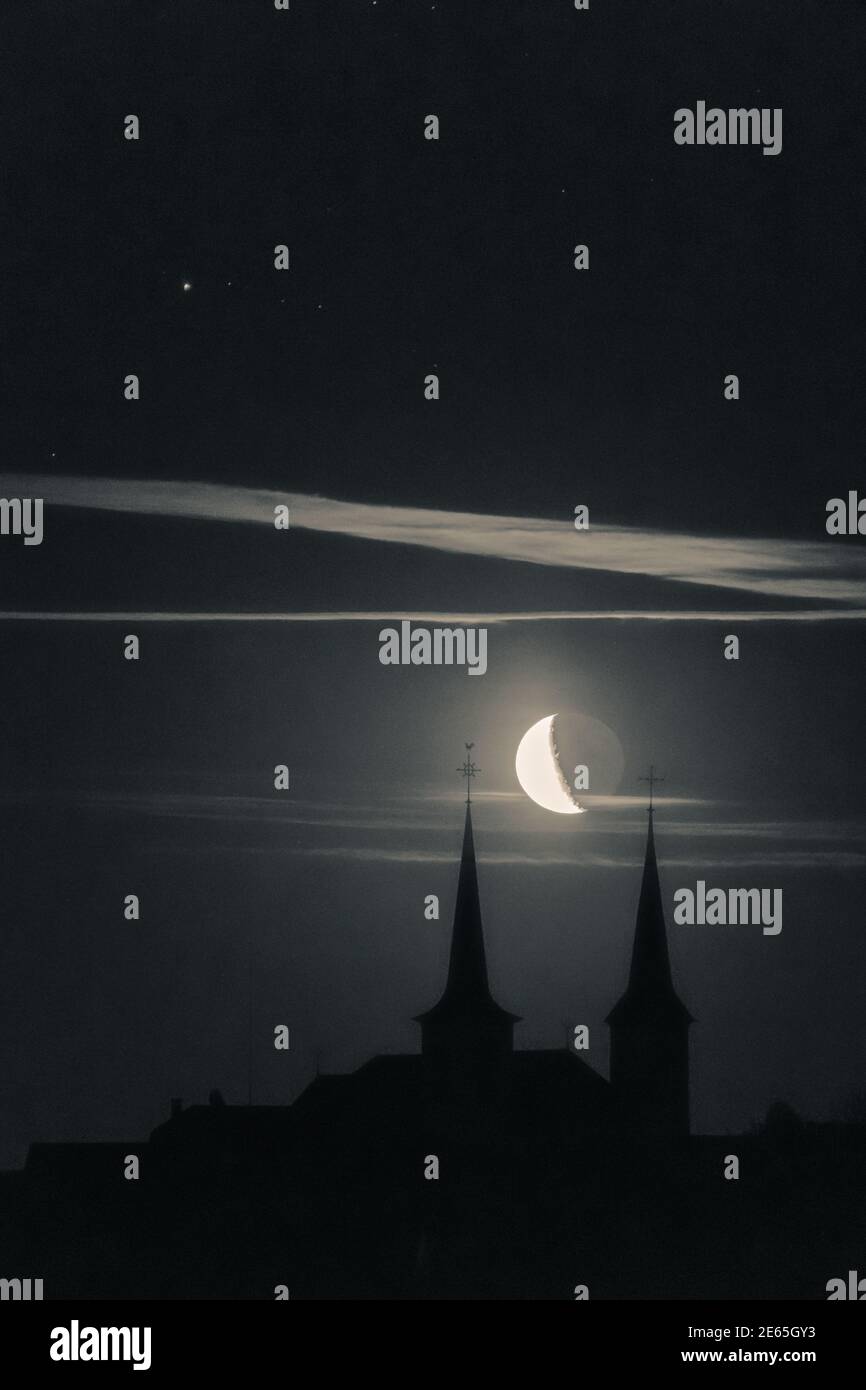 Crescent moon rising between two towers of a church of a small german ...