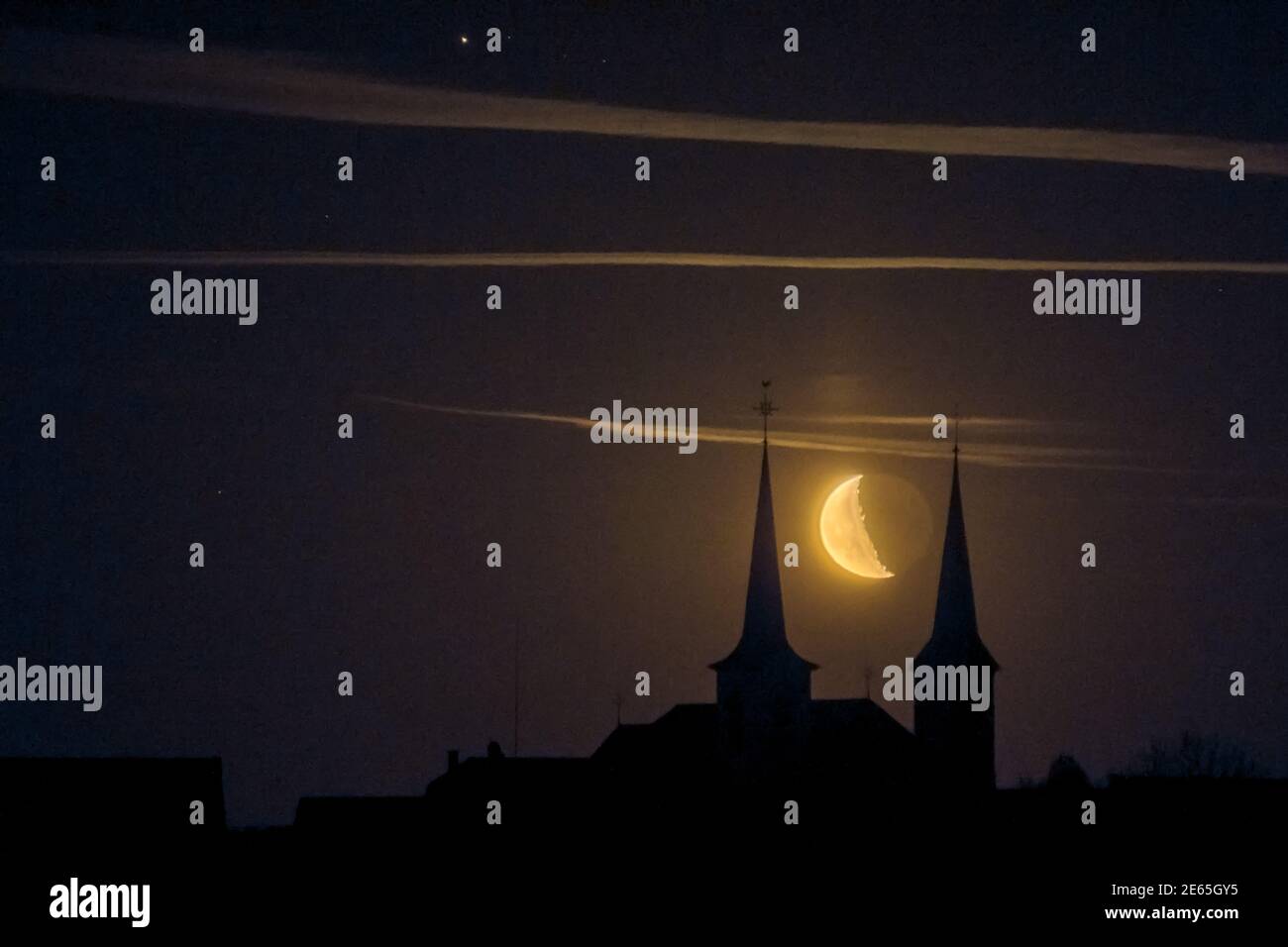 Crescent moon rising between two towers of a church of a small german ...