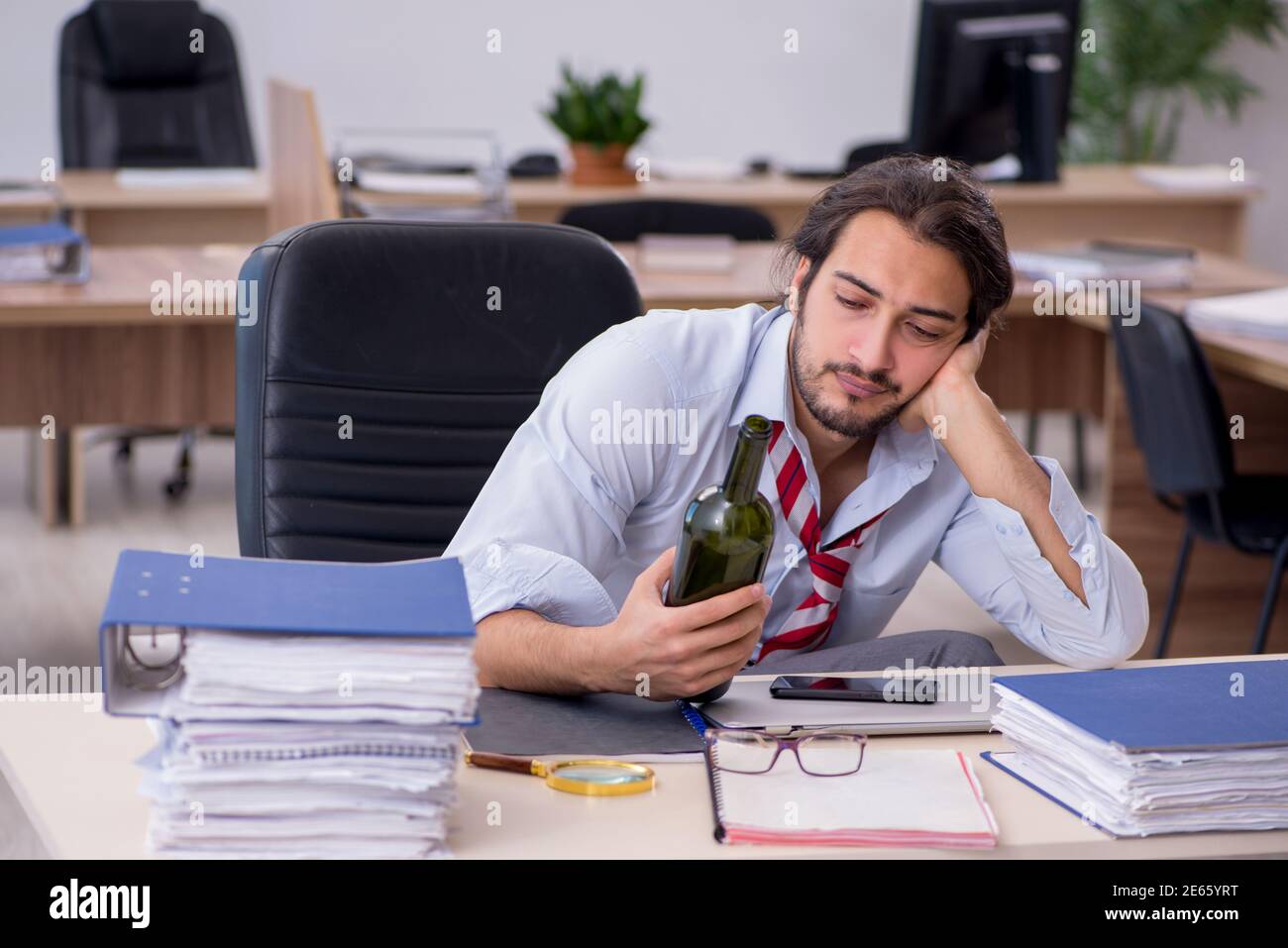 Young male employee drinking alcohol at workplace Stock Photo - Alamy