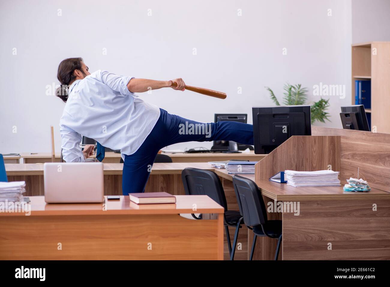 Young furious employee holding baseball bat in the office Stock Photo ...