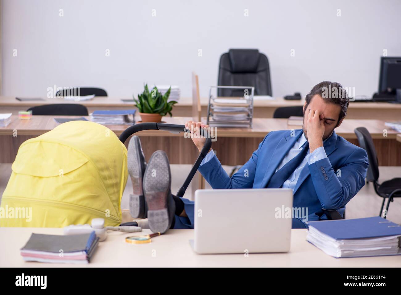Young male employee looking after new born in the office Stock Photo ...