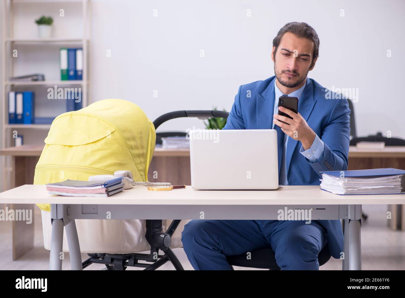 Young male employee looking after new born in the office Stock Photo ...
