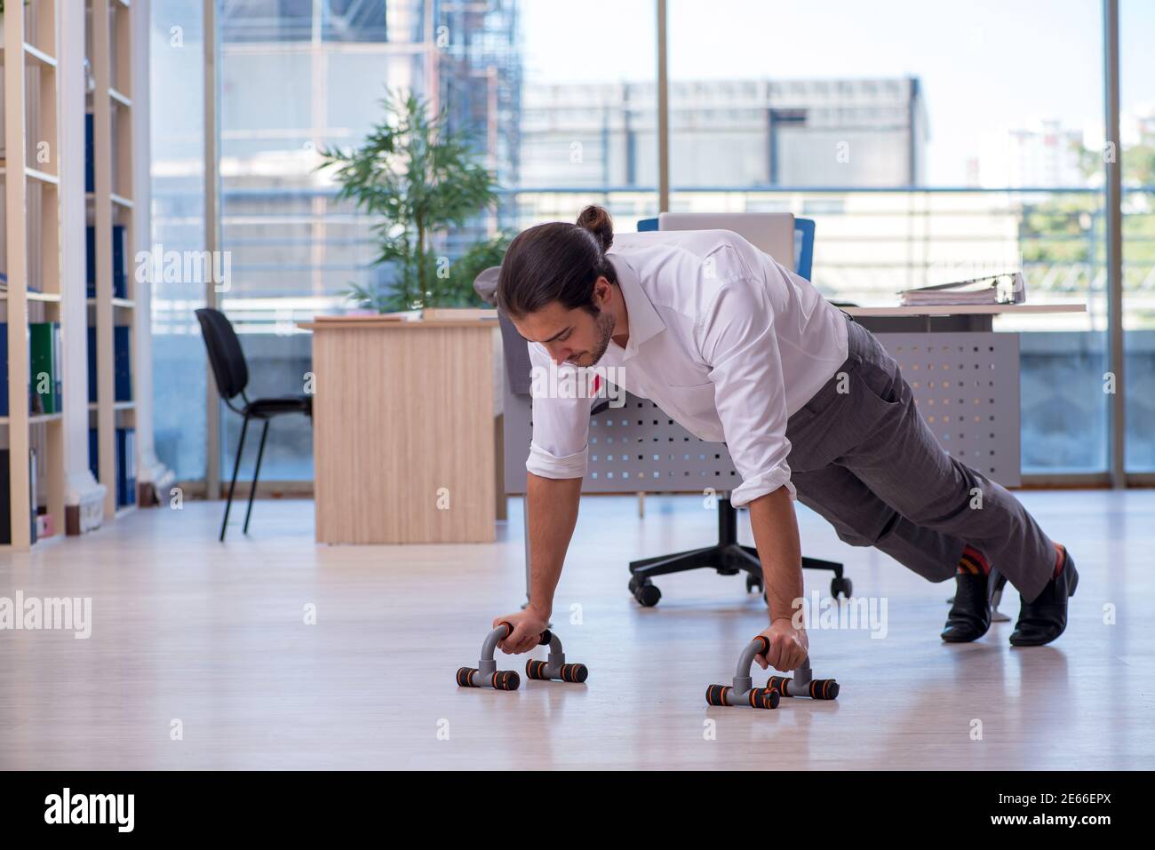 Young employee doing sport exercises at workplace Stock Photo - Alamy