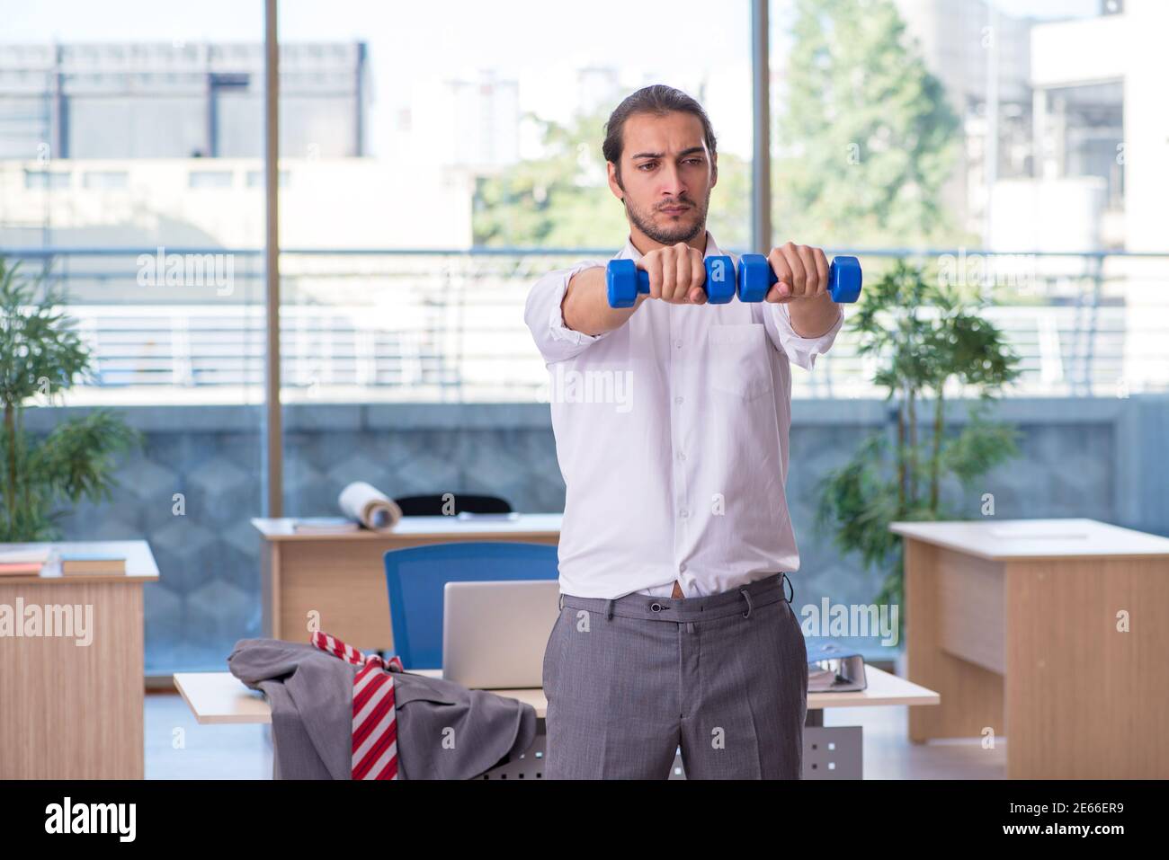 Young employee doing sport exercises at workplace Stock Photo - Alamy