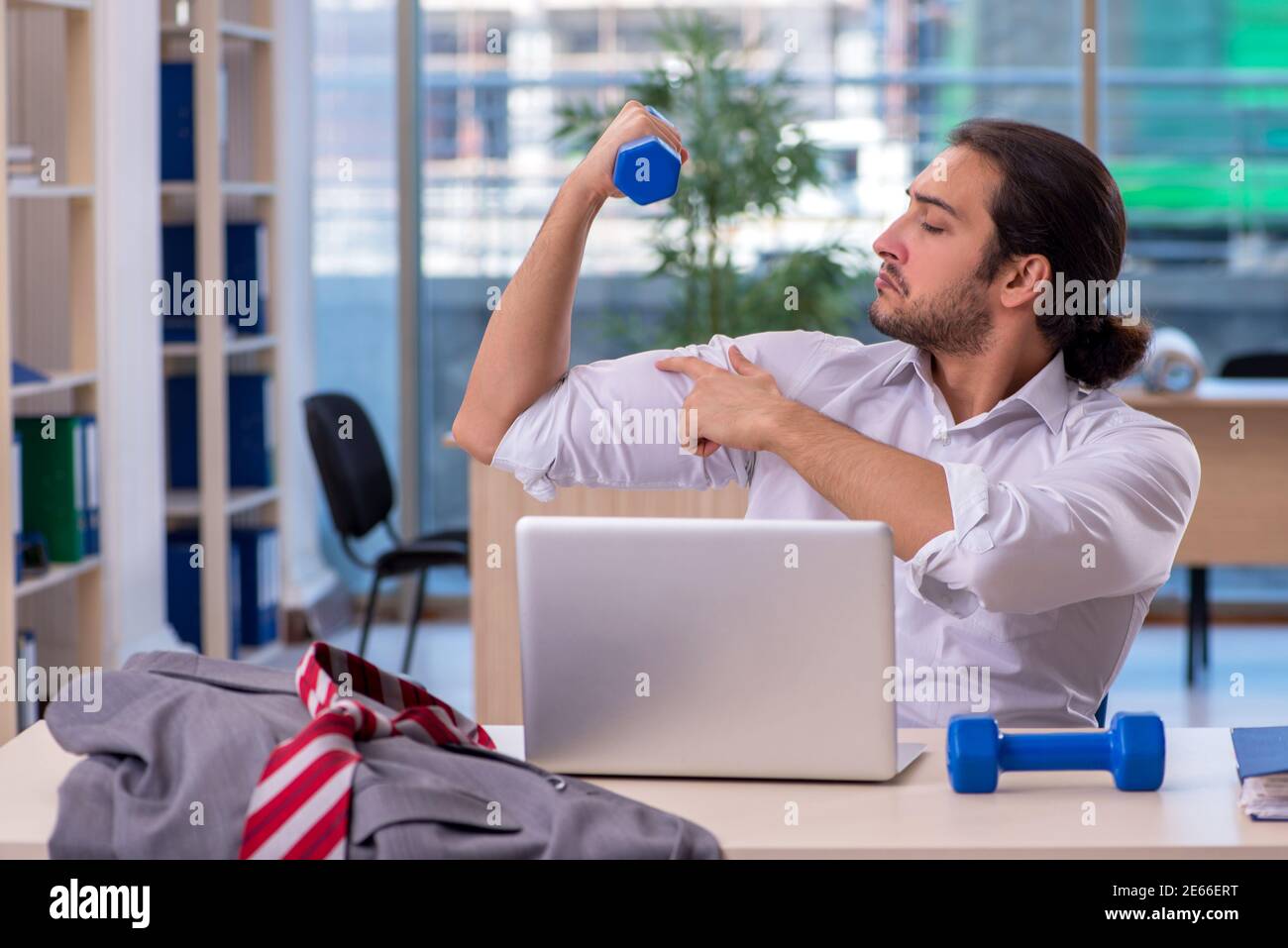 Young employee doing sport exercises at workplace Stock Photo - Alamy