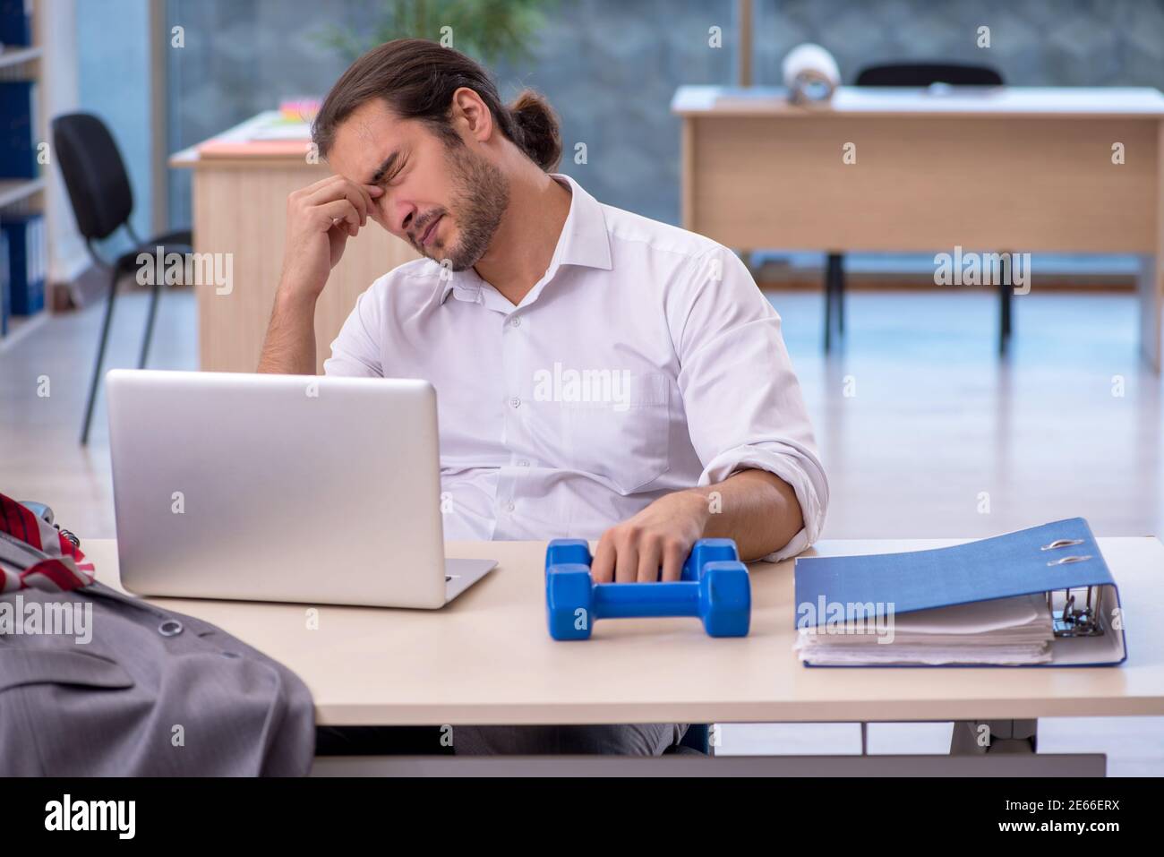 Young employee doing sport exercises at workplace Stock Photo - Alamy
