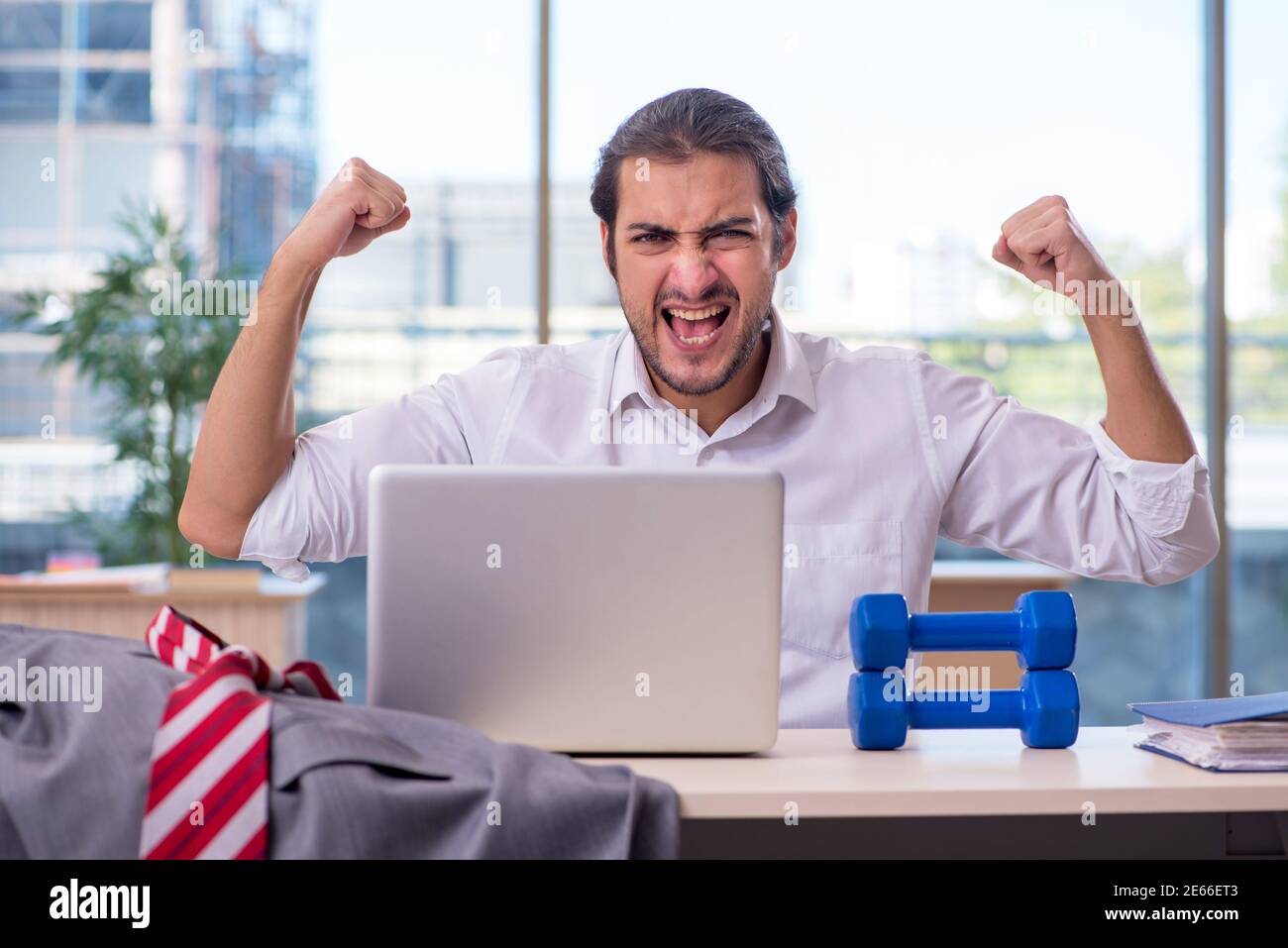 Young employee doing sport exercises at workplace Stock Photo - Alamy
