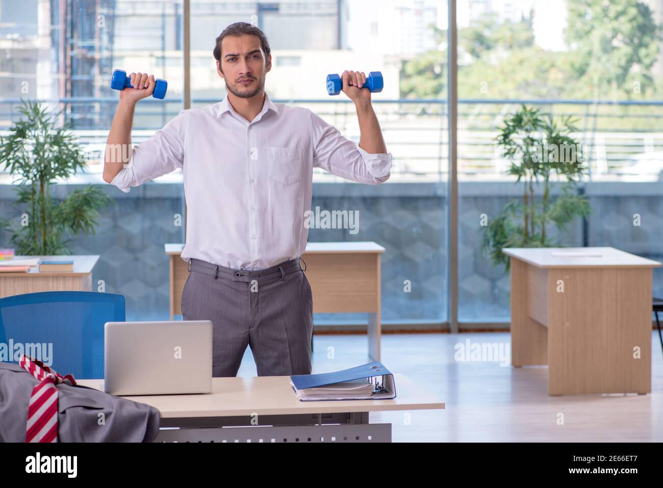 Young employee doing sport exercises at workplace Stock Photo - Alamy