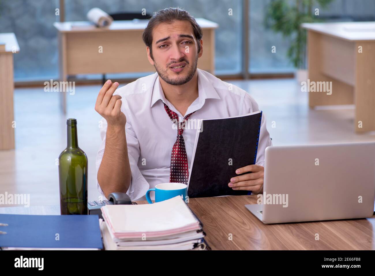 Young alcohol addicted employee working in the office Stock Photo - Alamy