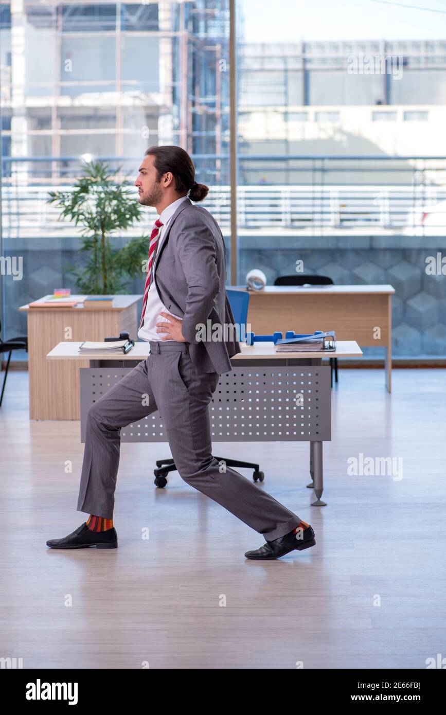 Young employee doing sport exercises at workplace Stock Photo - Alamy