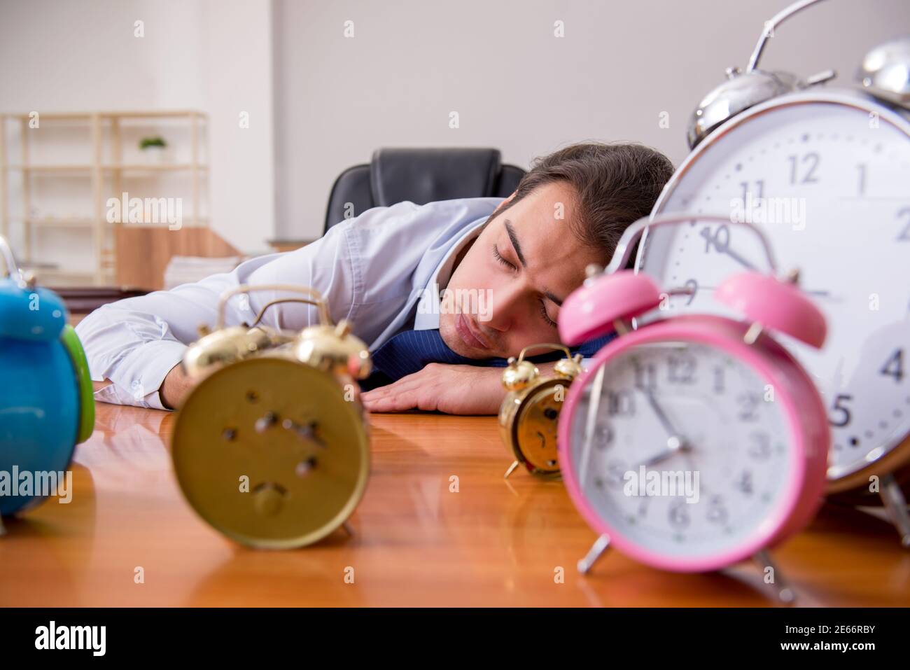 Young businessman sleeping in the office in time management concept ...